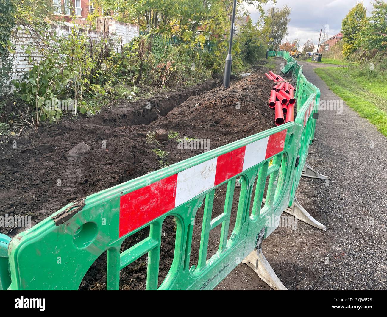 road excavation surrounded by green safety barriers and tools ...