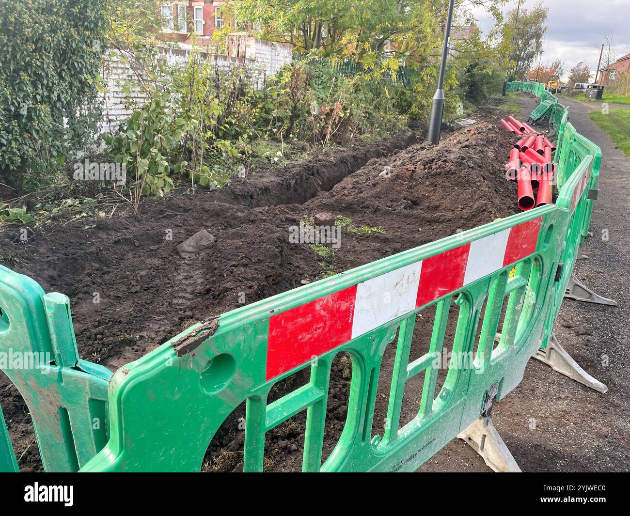 road excavation surrounded by green safety barriers and tools ...