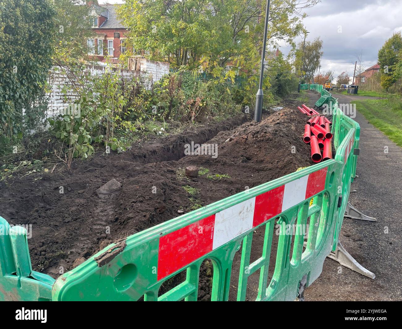 road excavation surrounded by green safety barriers and tools ...