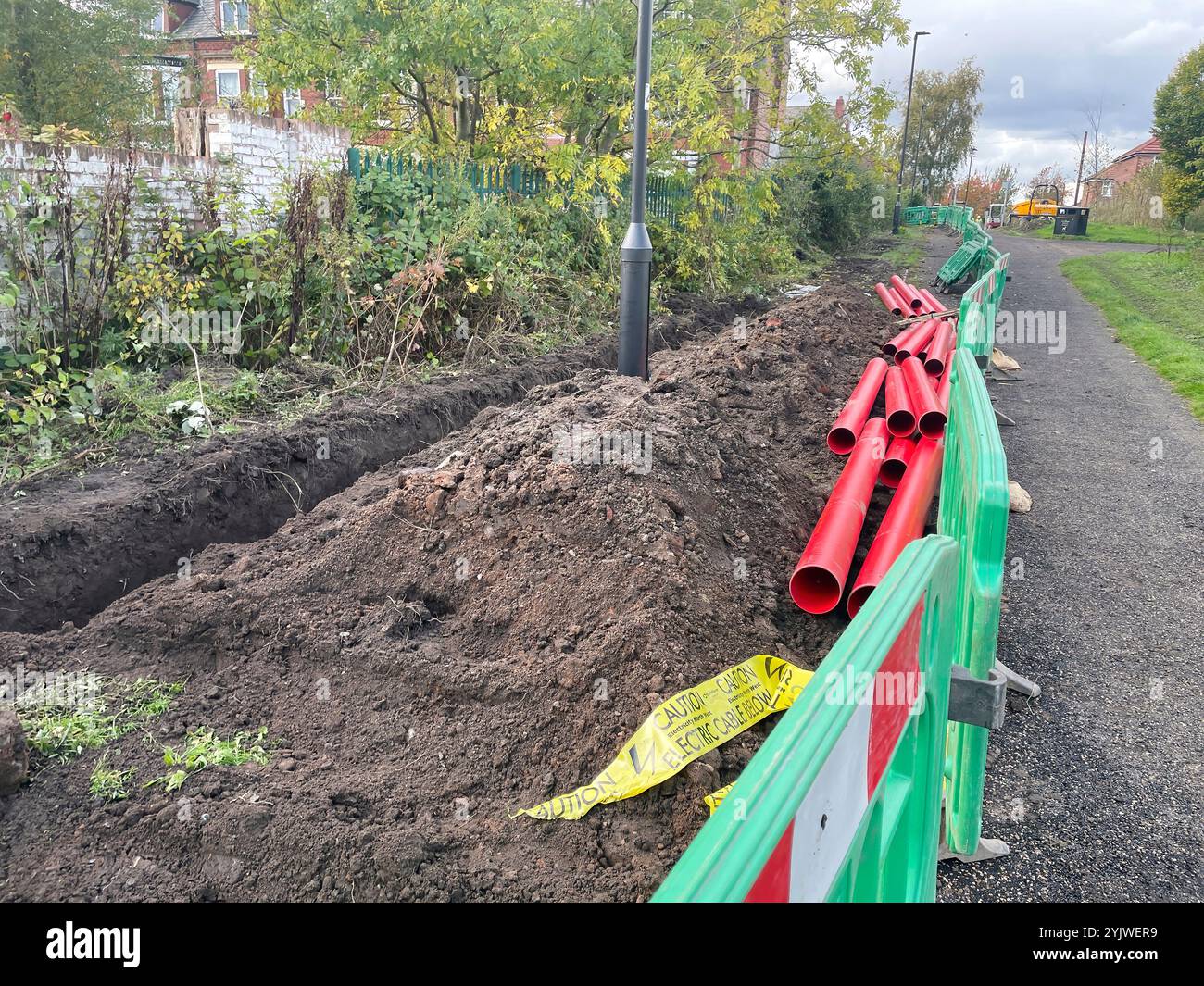 road excavation surrounded by green safety barriers and tools ...