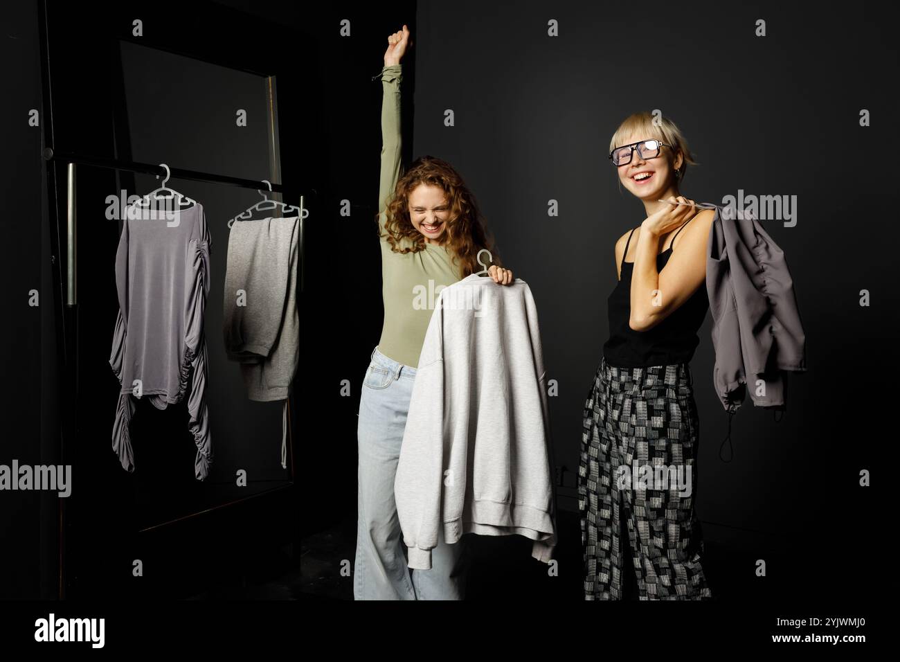 Beautiful young woman stylist designer helping choose clothes to ...