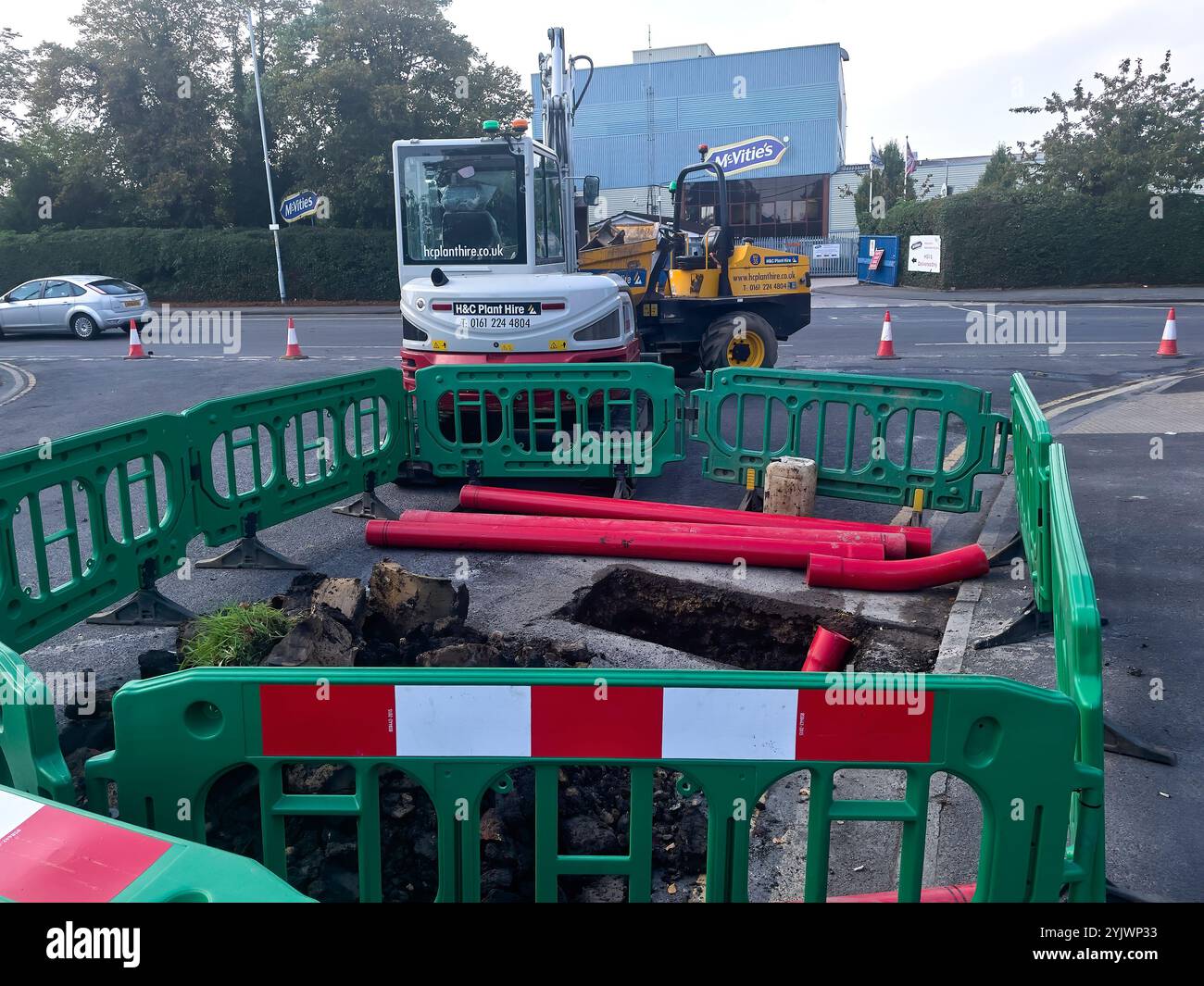 road excavation surrounded by green safety barriers and tools ...