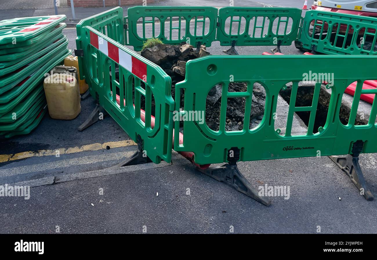 road excavation surrounded by green safety barriers and tools ...