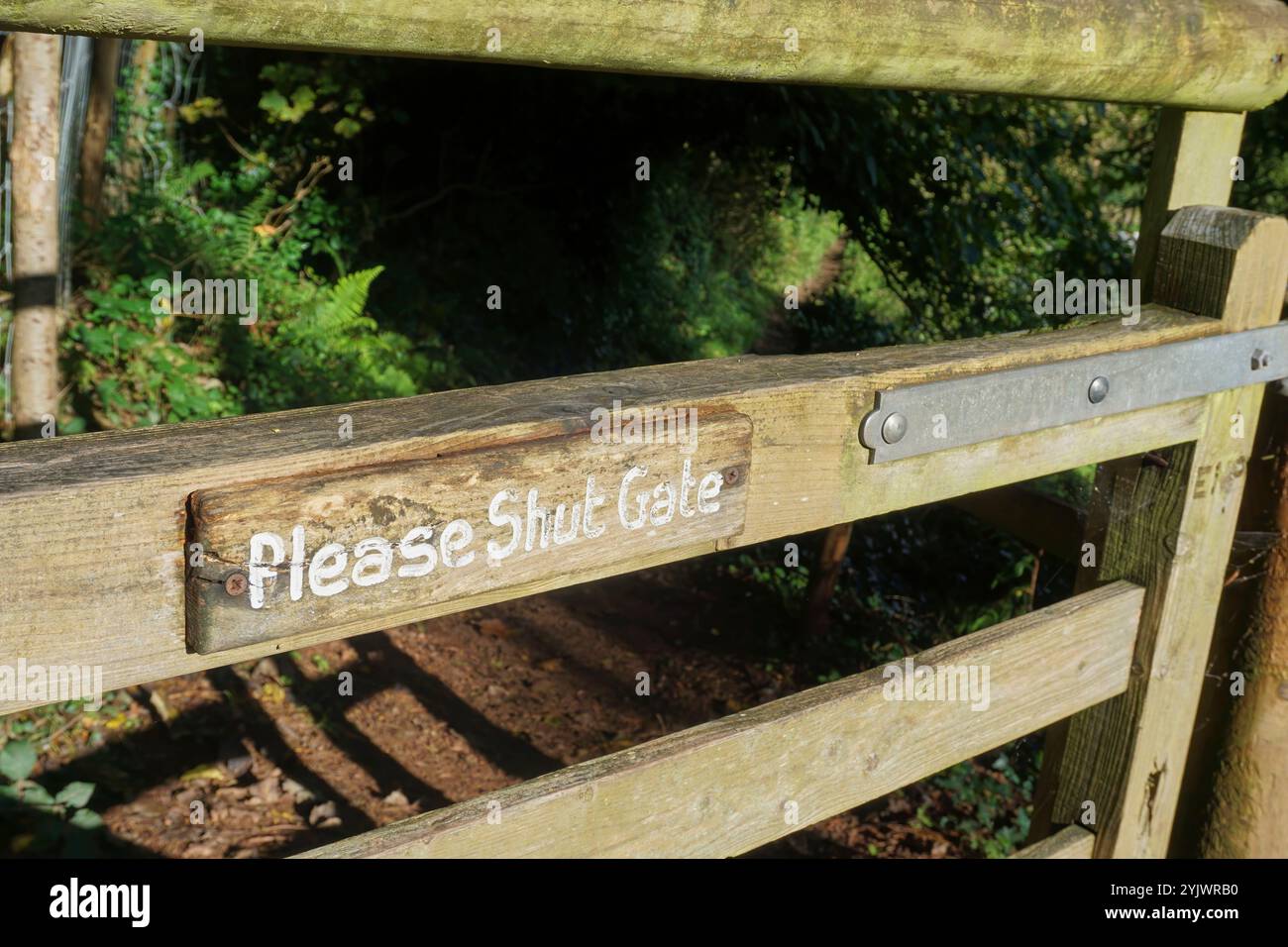 A countryside wooden gate with an engraved sign reading "Please Shut ...