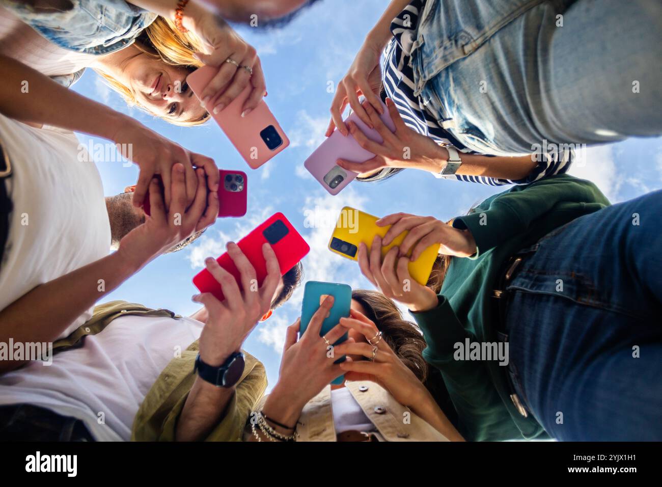 Group of young people using mobile phones against blue sky Stock Photo ...
