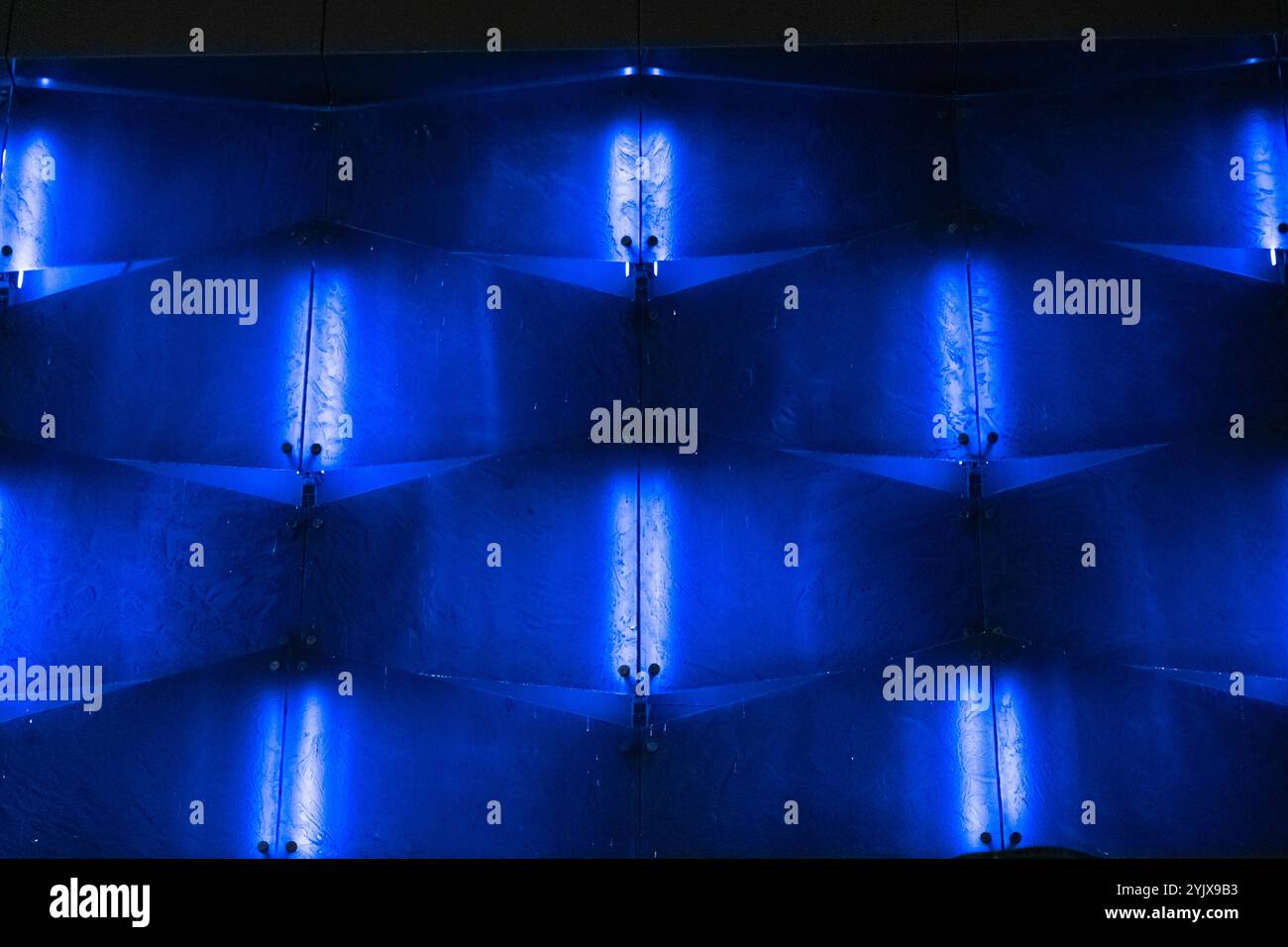 The illuminated, blue, glass facade of the building at night. Glazed ...
