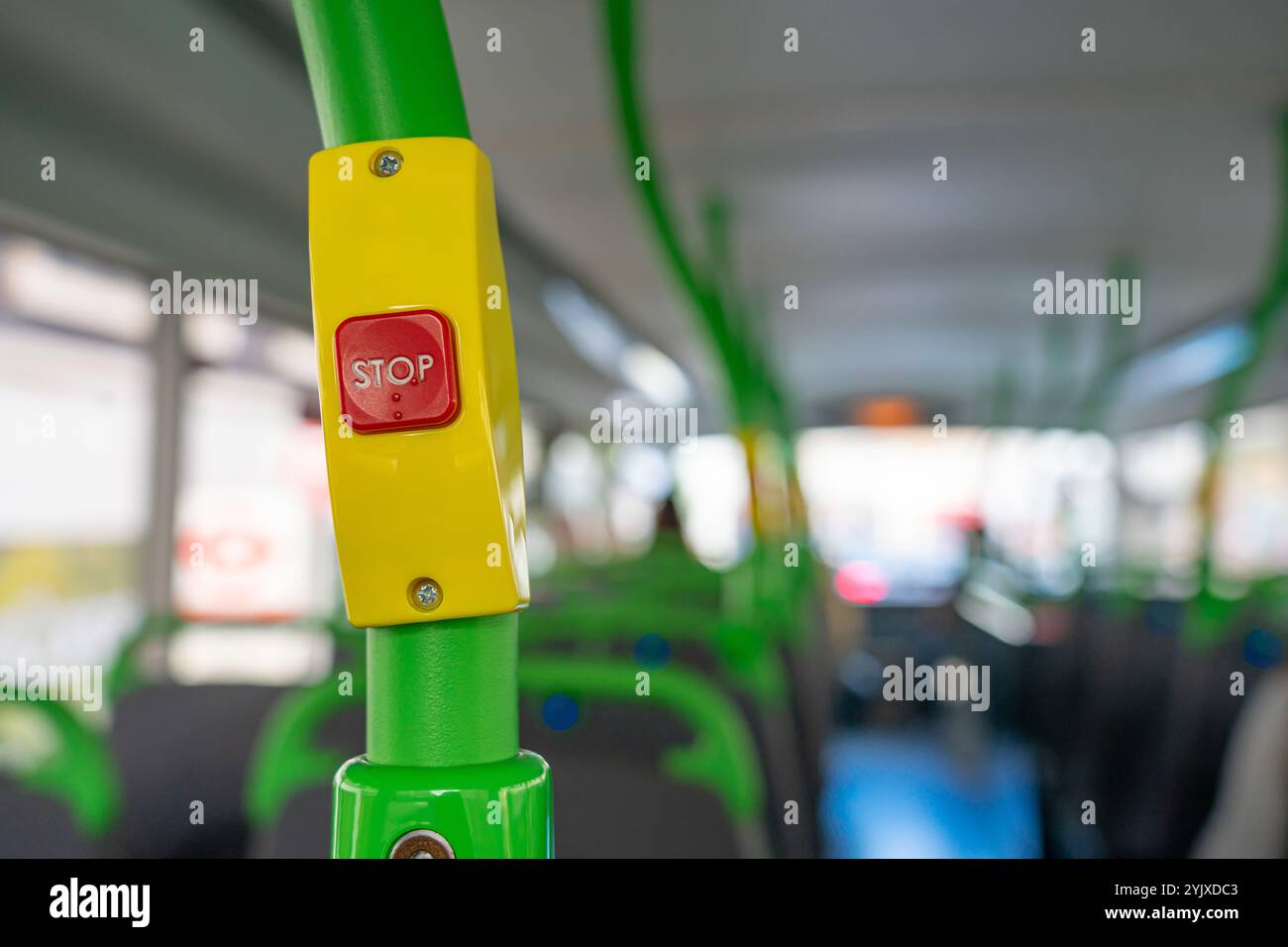 red stop button wrapped in yellow casing and green pole on a bus in ...