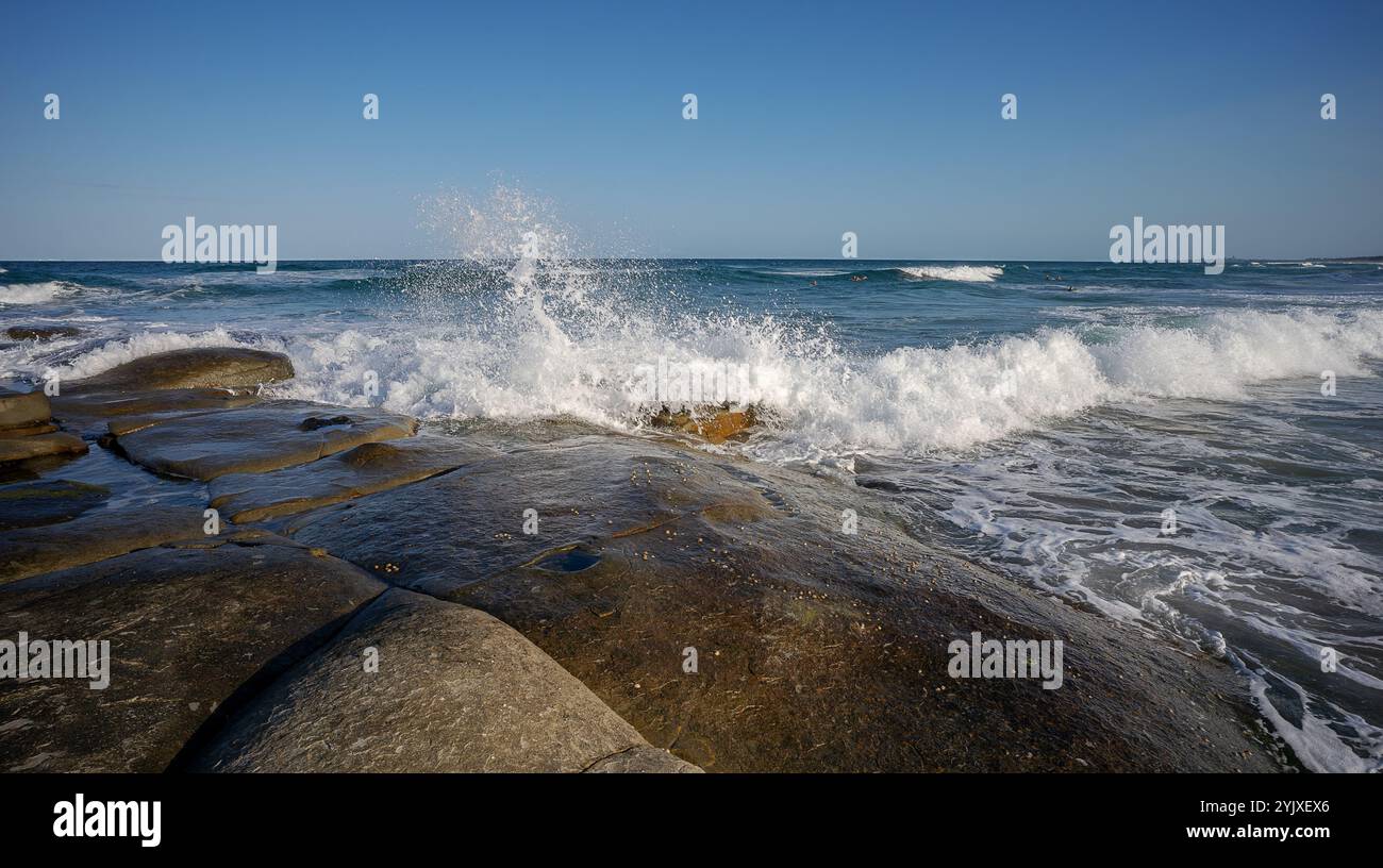 White foaming water splashes as surf waves break over large rock ...