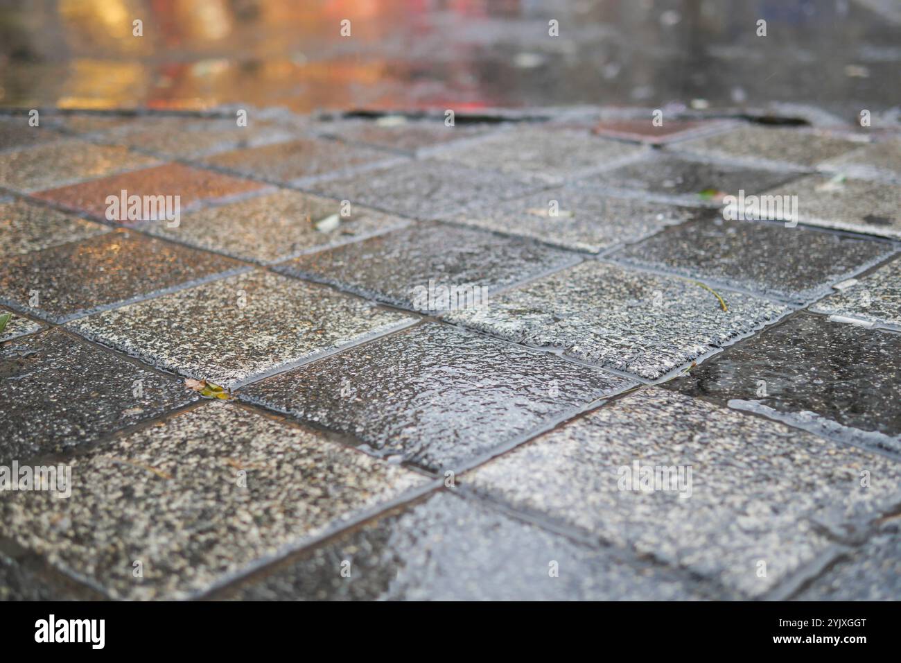 A wet, paved surface exhibiting highly reflective tiles during rainy ...