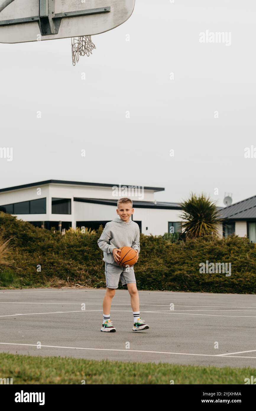 Happy boy throws ball into rim playing basketball on ground Stock Photo ...