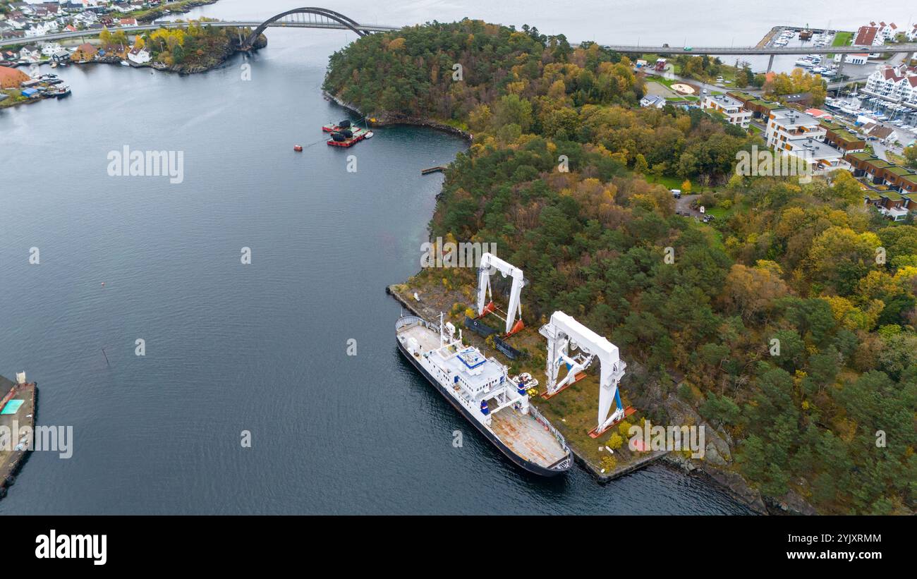 Aerial view of a large ship docked at an abandoned shipyard with two ...