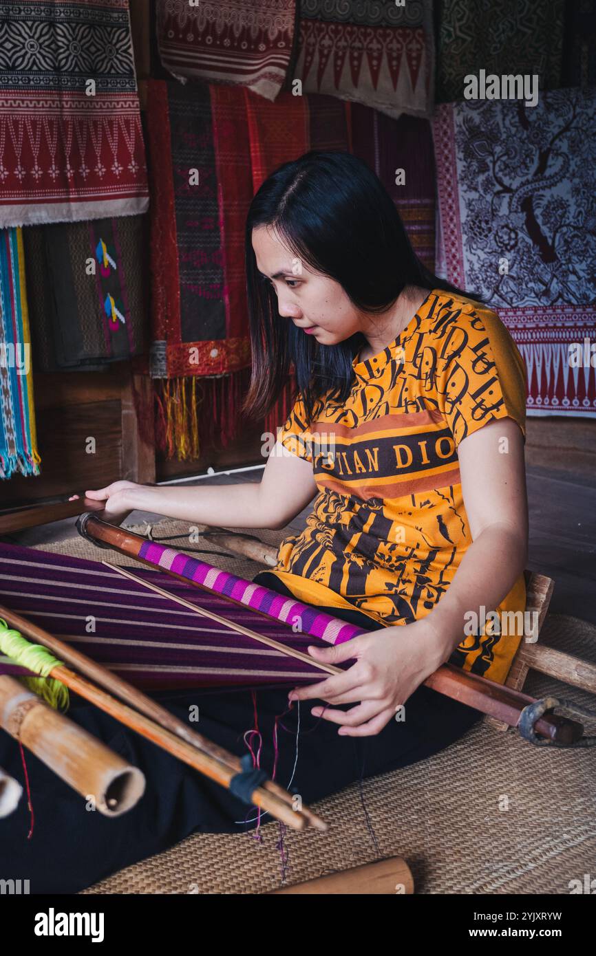 A Torajan Sa'dan weaver woman works on her weaving, October 2, 2024 ...