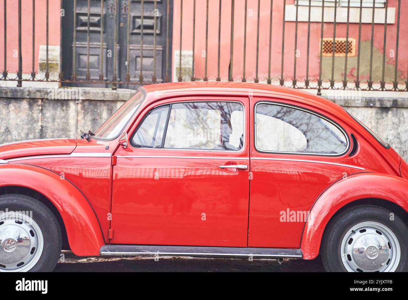 Red car parked by building, its wheels and tires visible Stock Photo ...