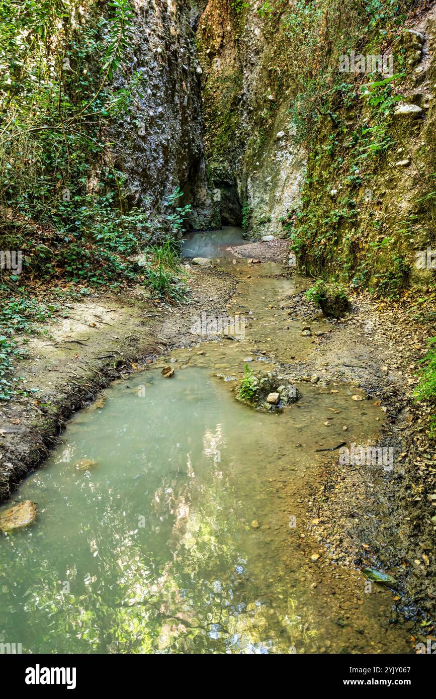 A narrow, calm stream winds through steep, rocky walls in Peristerias ...