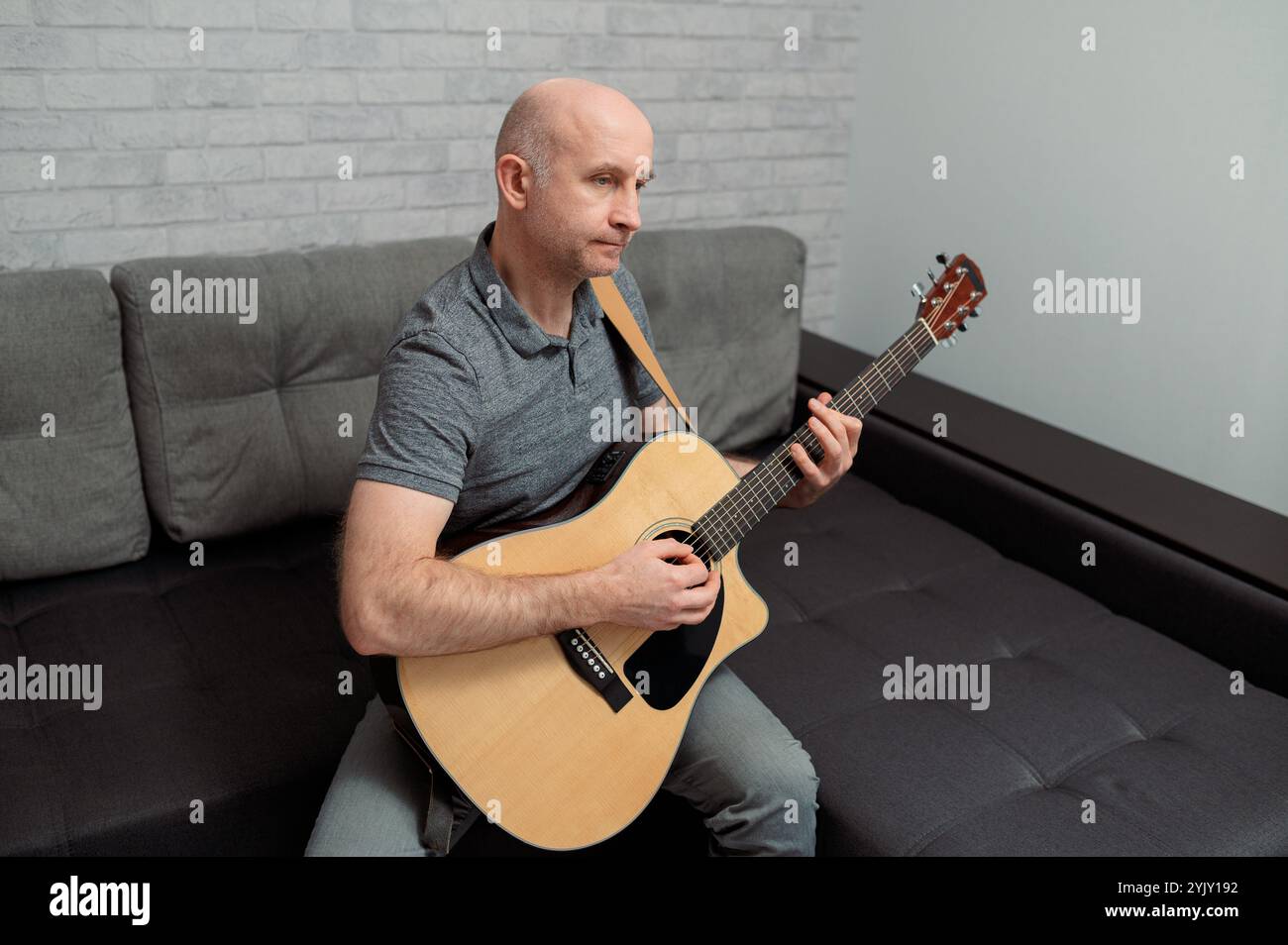 man guitarist playing guitar at home. Relaxing and sitting on sofa ...