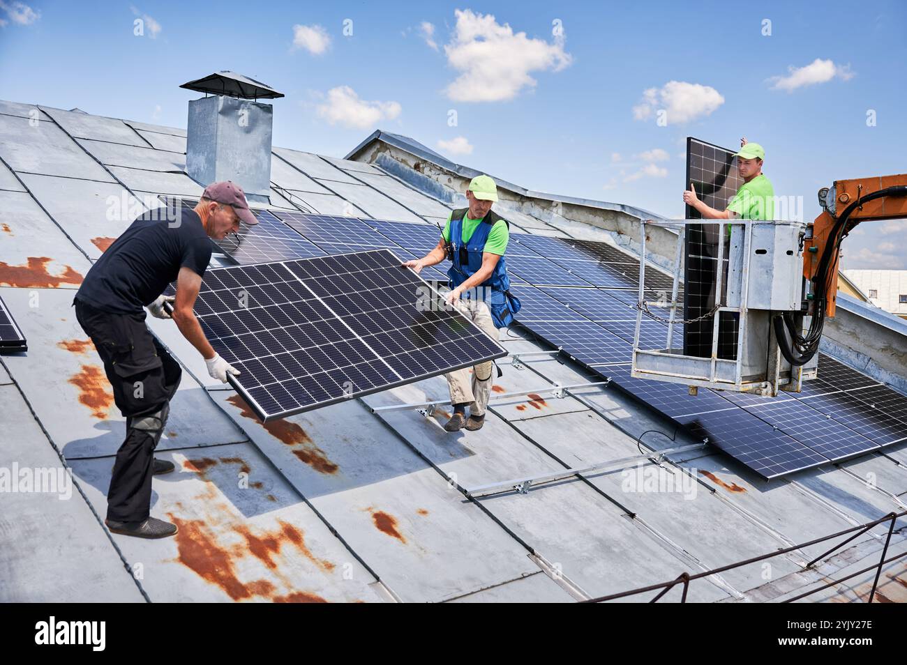 Workers building solar panel system on metal rooftop of house with ...