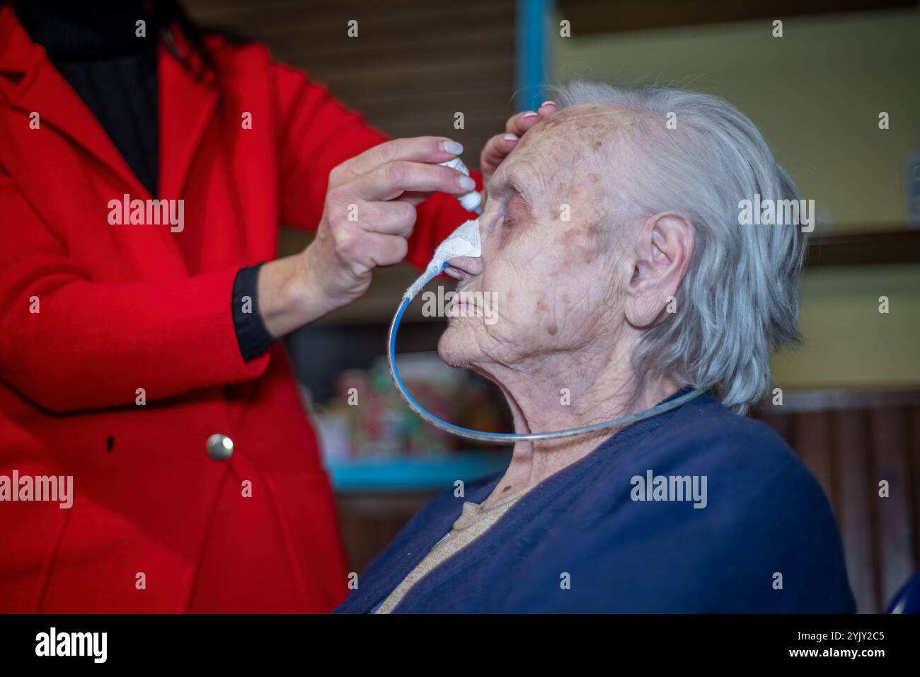 An elderly woman with a food cannula in her nose gets medication at ...