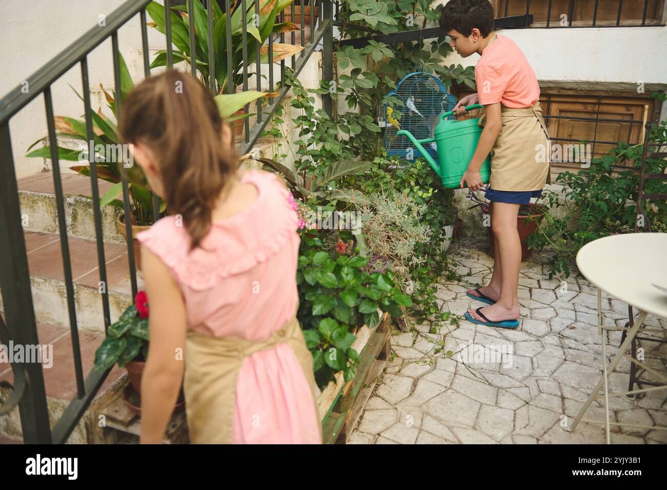 Two children engage in gardening, focusing on watering plants with a ...