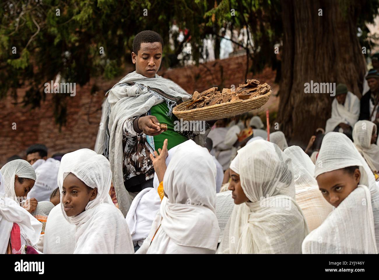 Altar boy distributes blessed bread to believers in traditional white ...