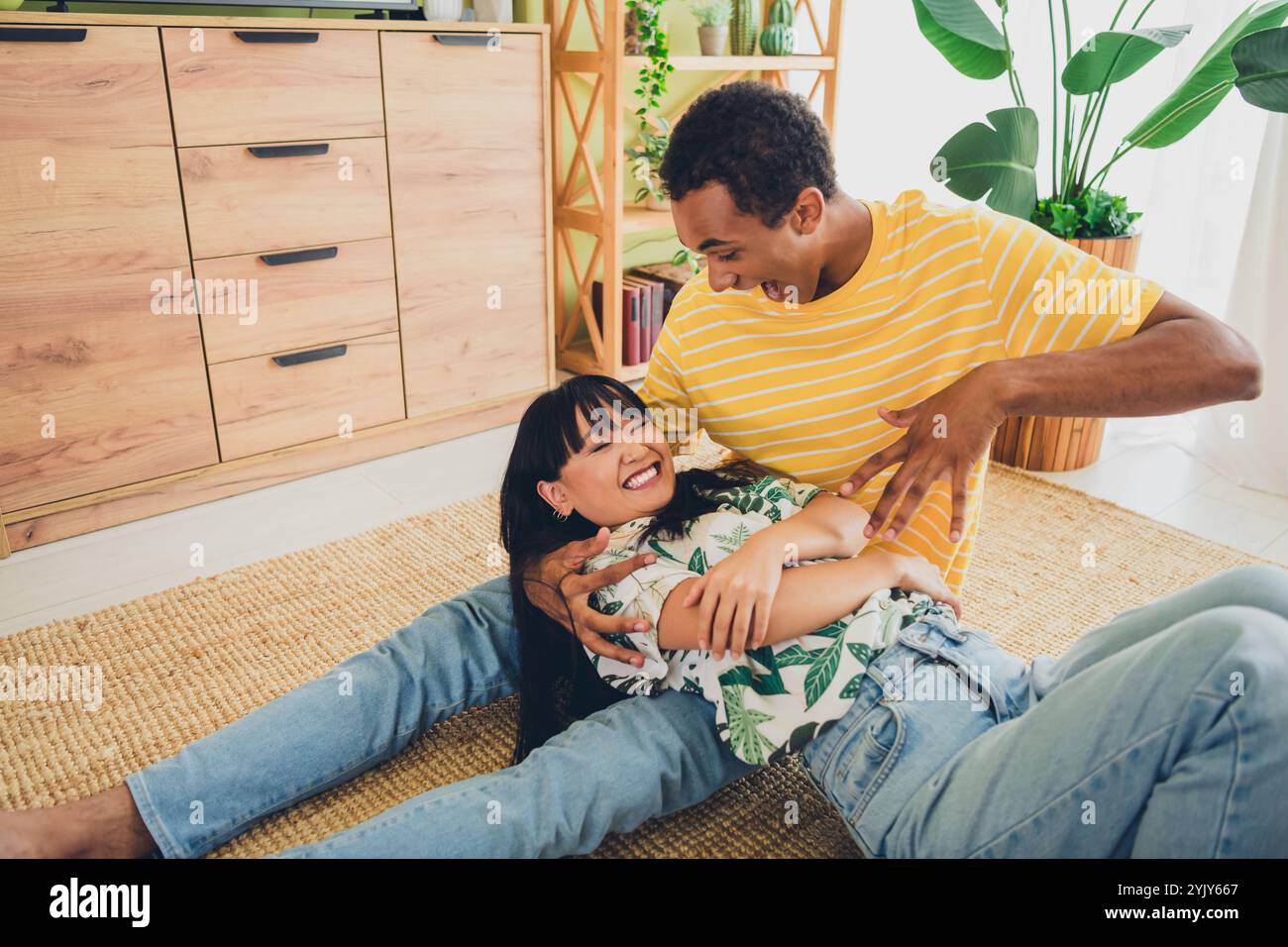 Photo of cheerful multinational couple having fun hugging tickling ...