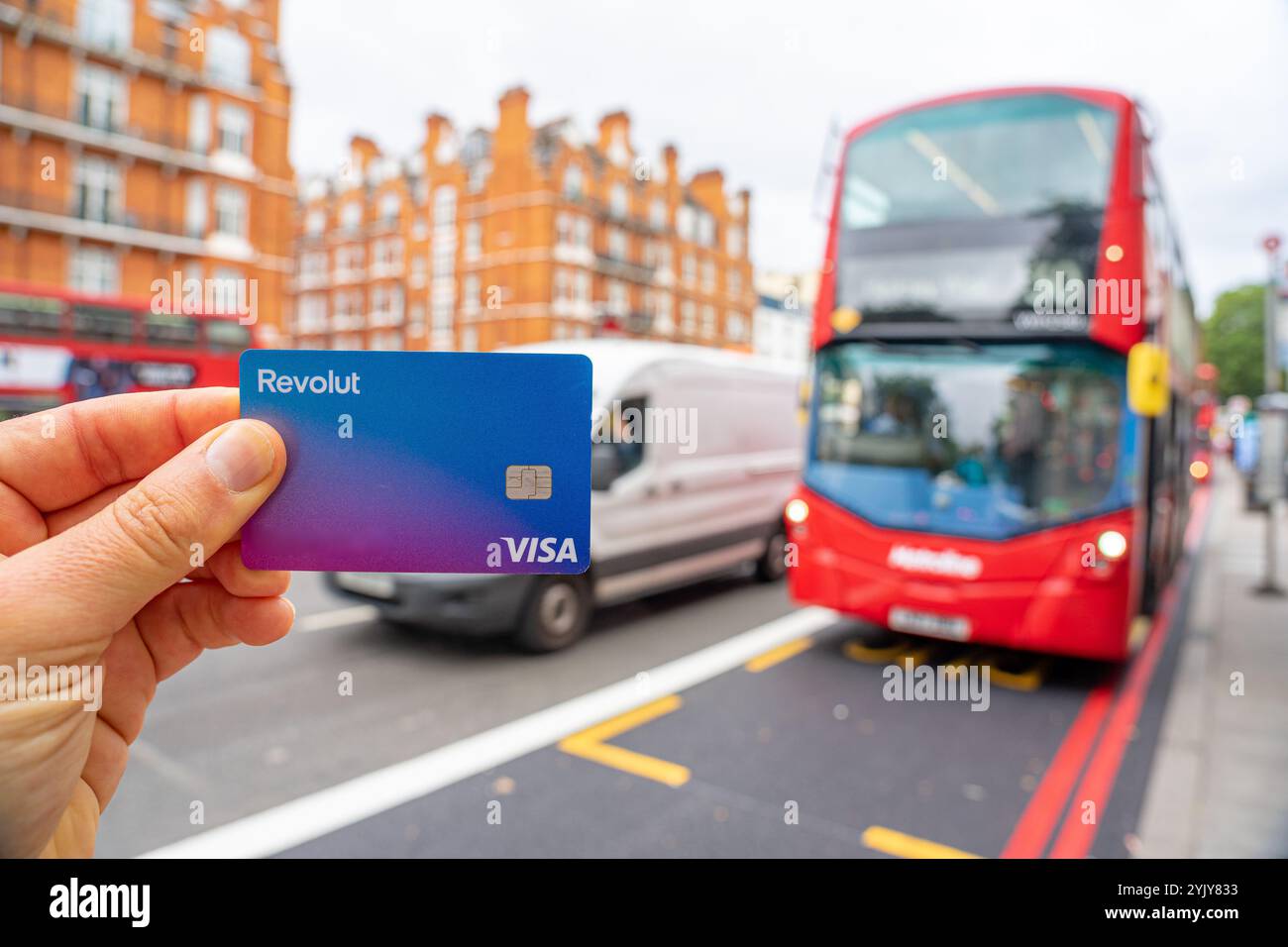 Visa revolut card in hand with blurred background of typical London ...