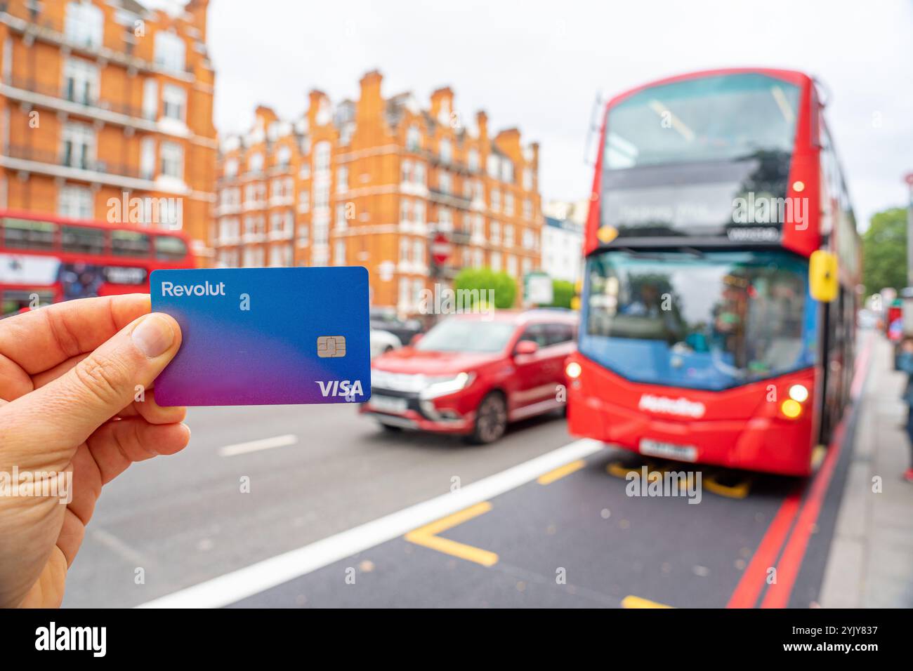 Visa revolut card in hand with blurred background of typical London ...