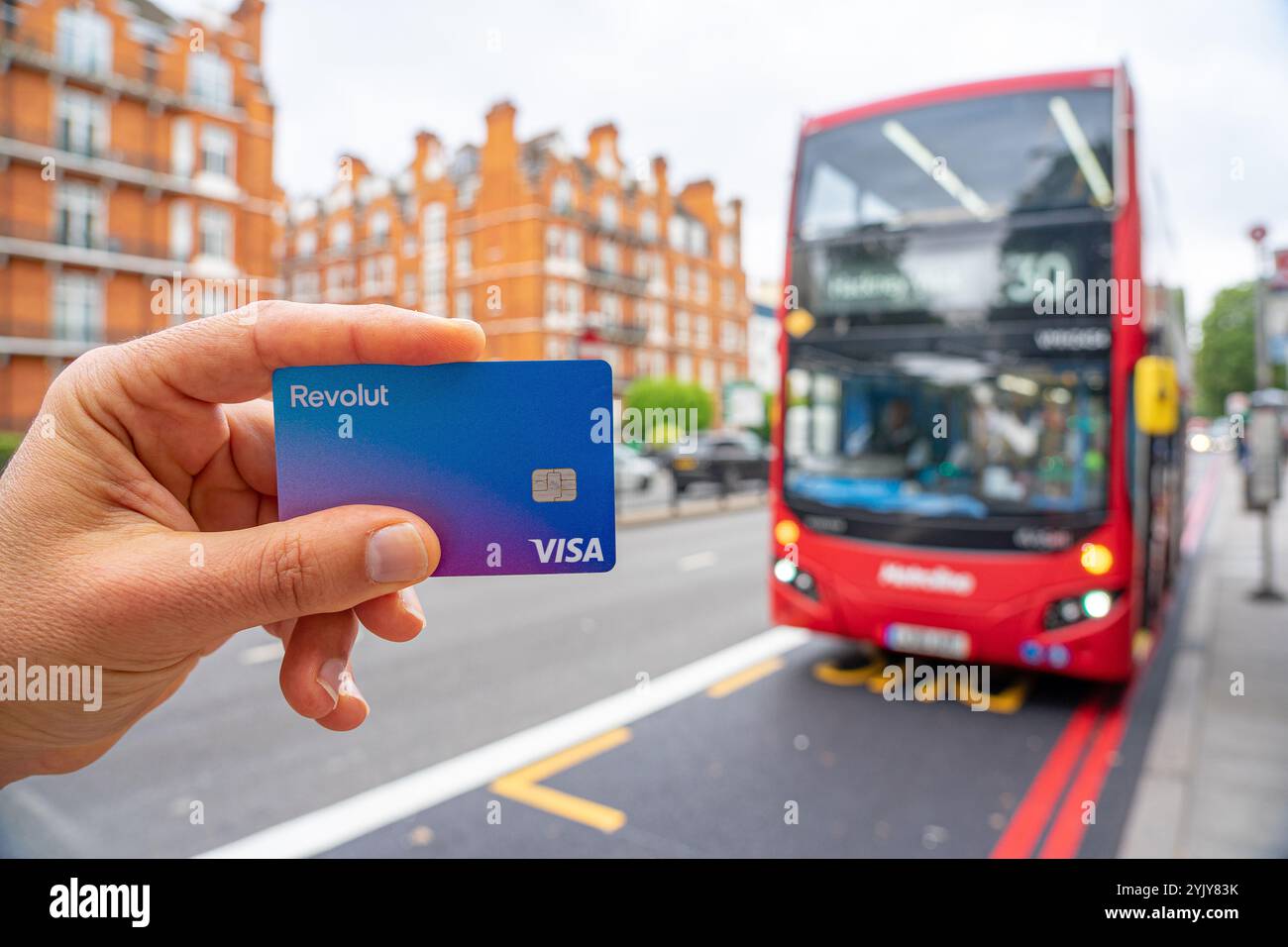 Visa revolut card in hand with blurred background of typical London ...