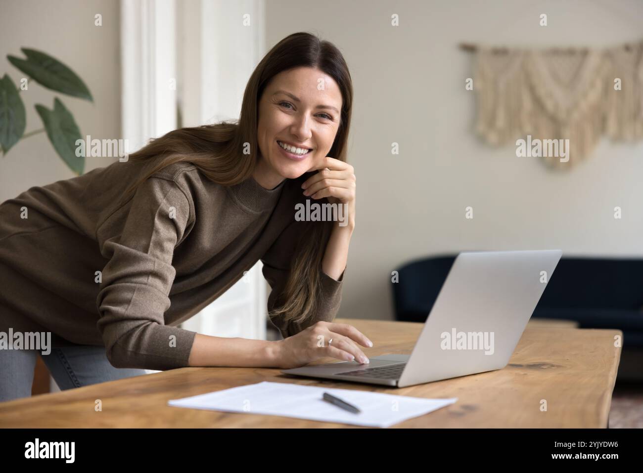 Portrait of self-employed woman leaning on desk with laptop Stock Photo ...