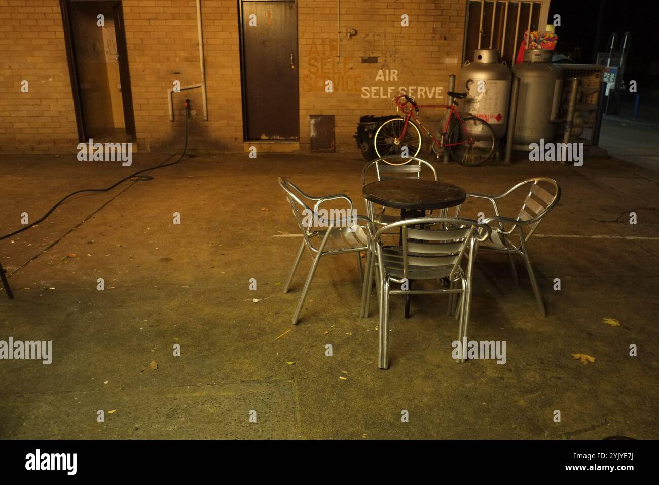 Cafe table with four silver charis on a patch of concrete at an empty ...
