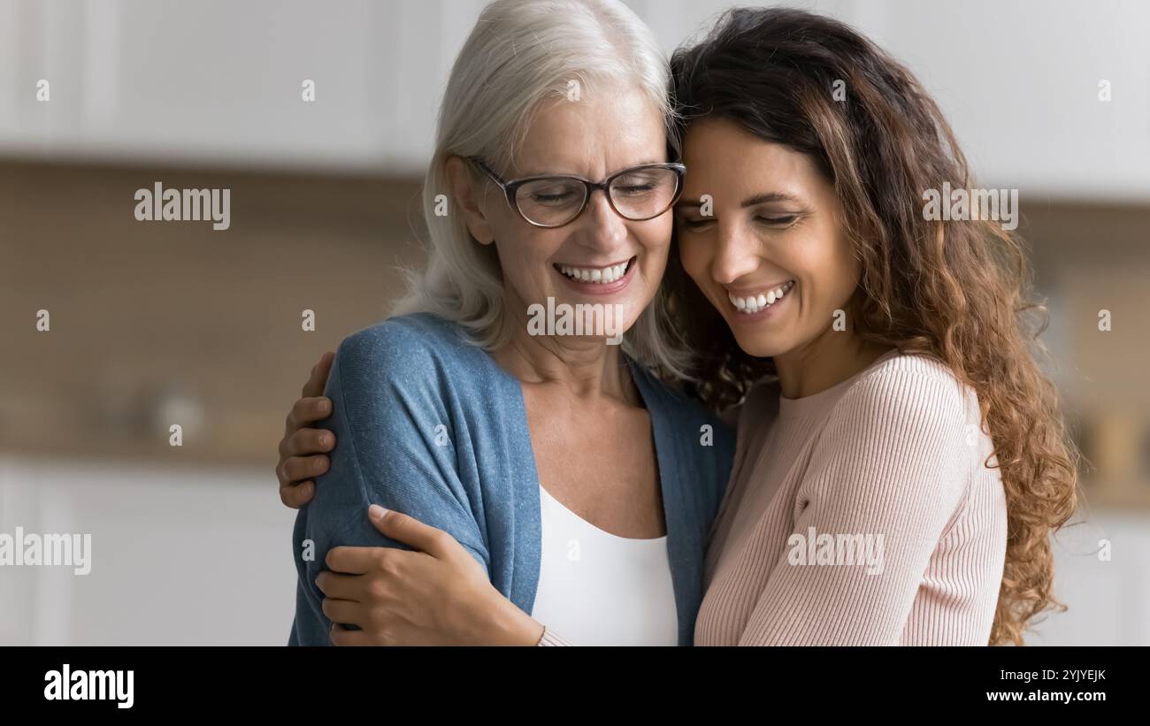 Two multigenerational women standing indoor and cuddling tightly Stock ...