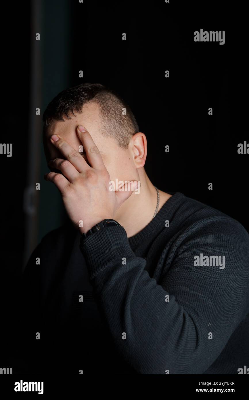 Expressive Portrait of a Man Concealing His Face in a Dimly Lit ...