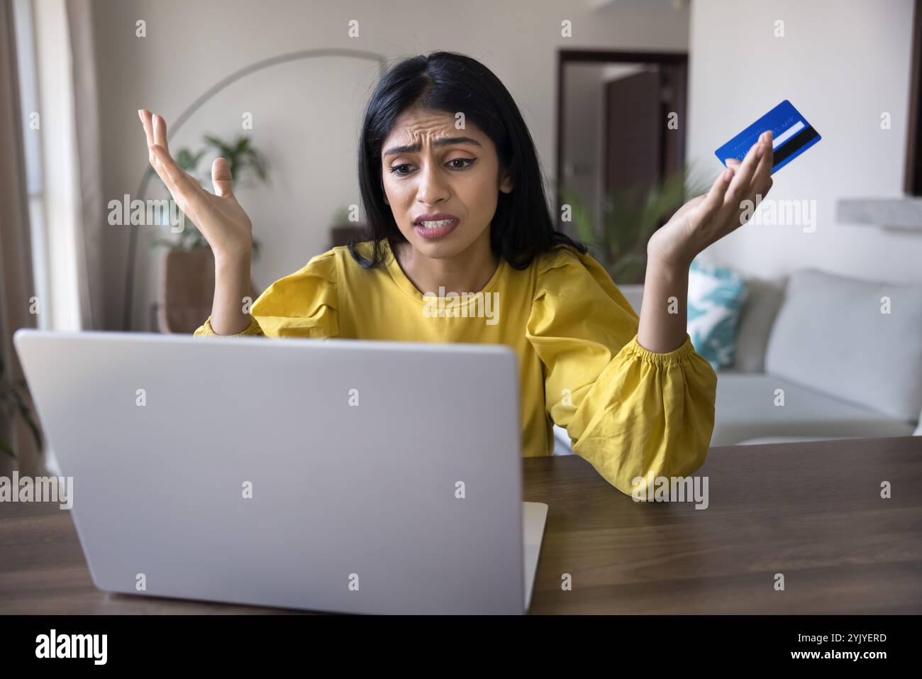 Annoyed young Indian bank client woman holding blue credit card Stock ...