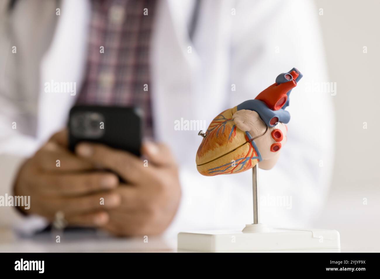 Artificial heart model and doctor on background using smartphone ...