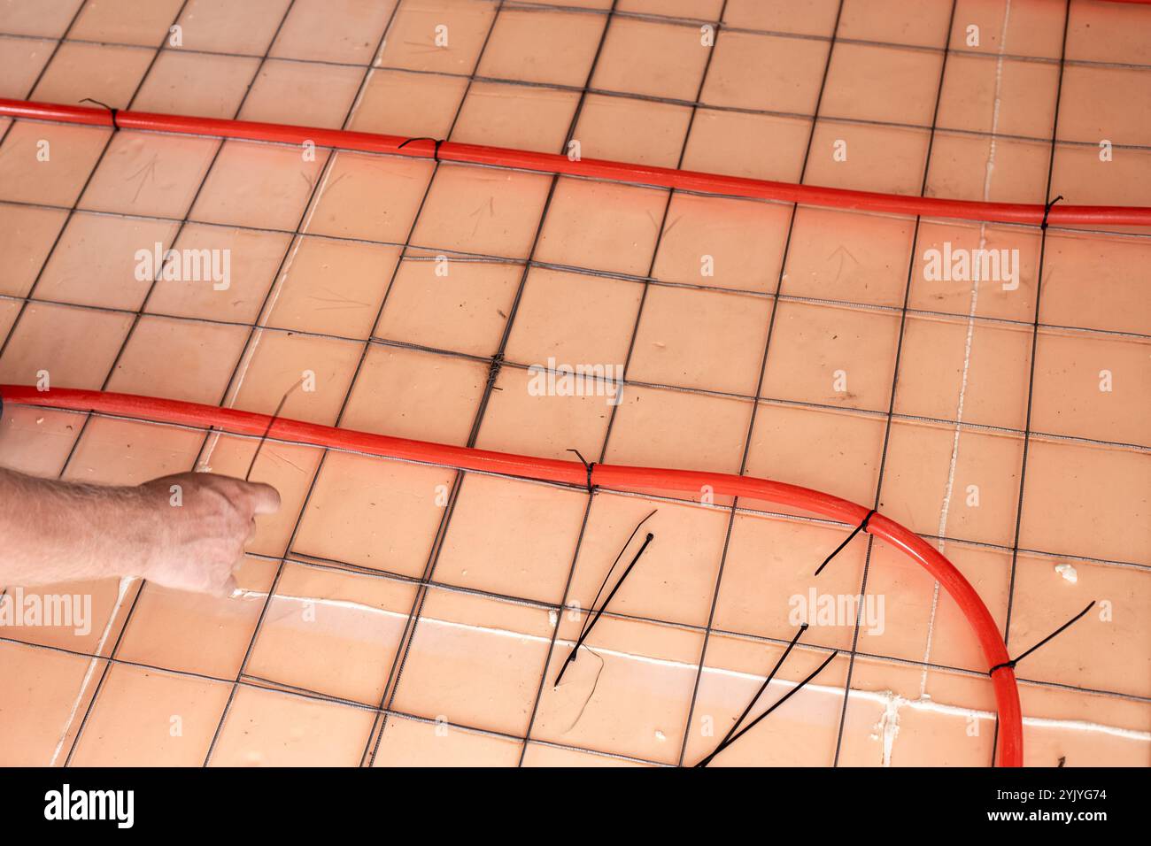 Installation of underfloor heating. A worker fastens pipes for ...