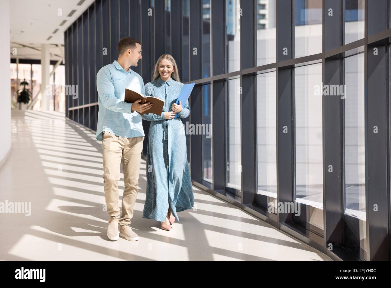 Couple of happy office friends walking in office hall Stock Photo - Alamy