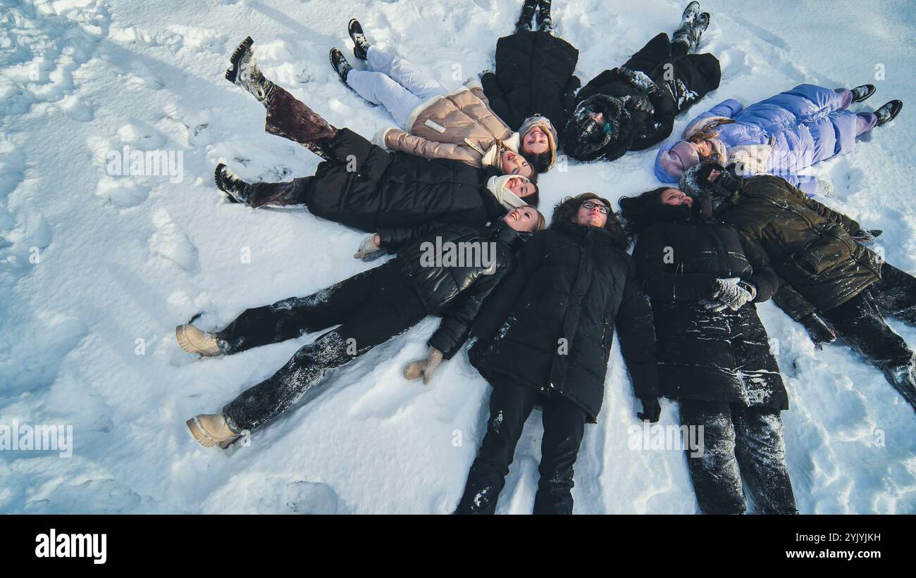 Friends lie in the snow on their backs in a circle shape Stock Photo ...