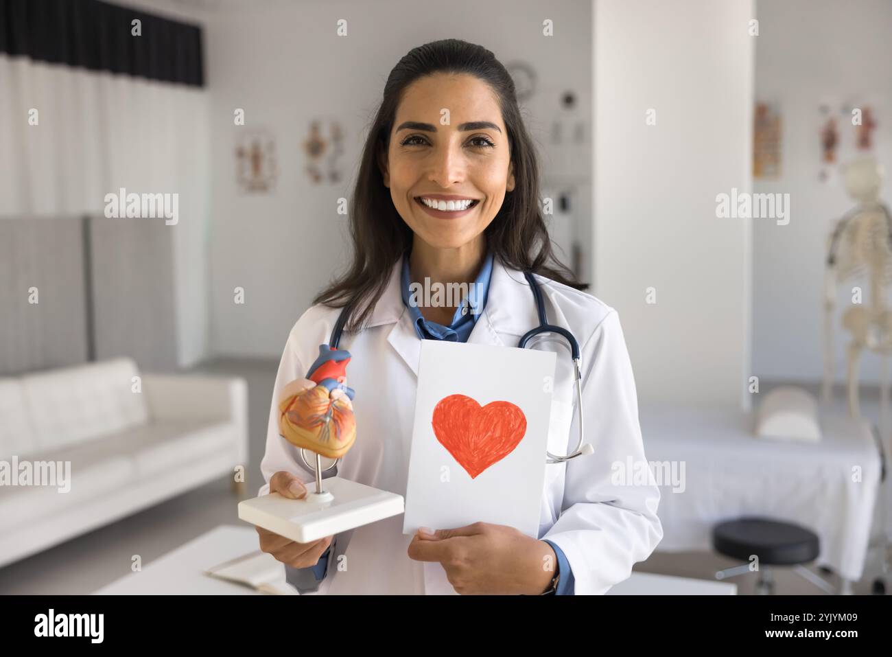 Cardiologist posing with postcard and anatomical human heart model ...