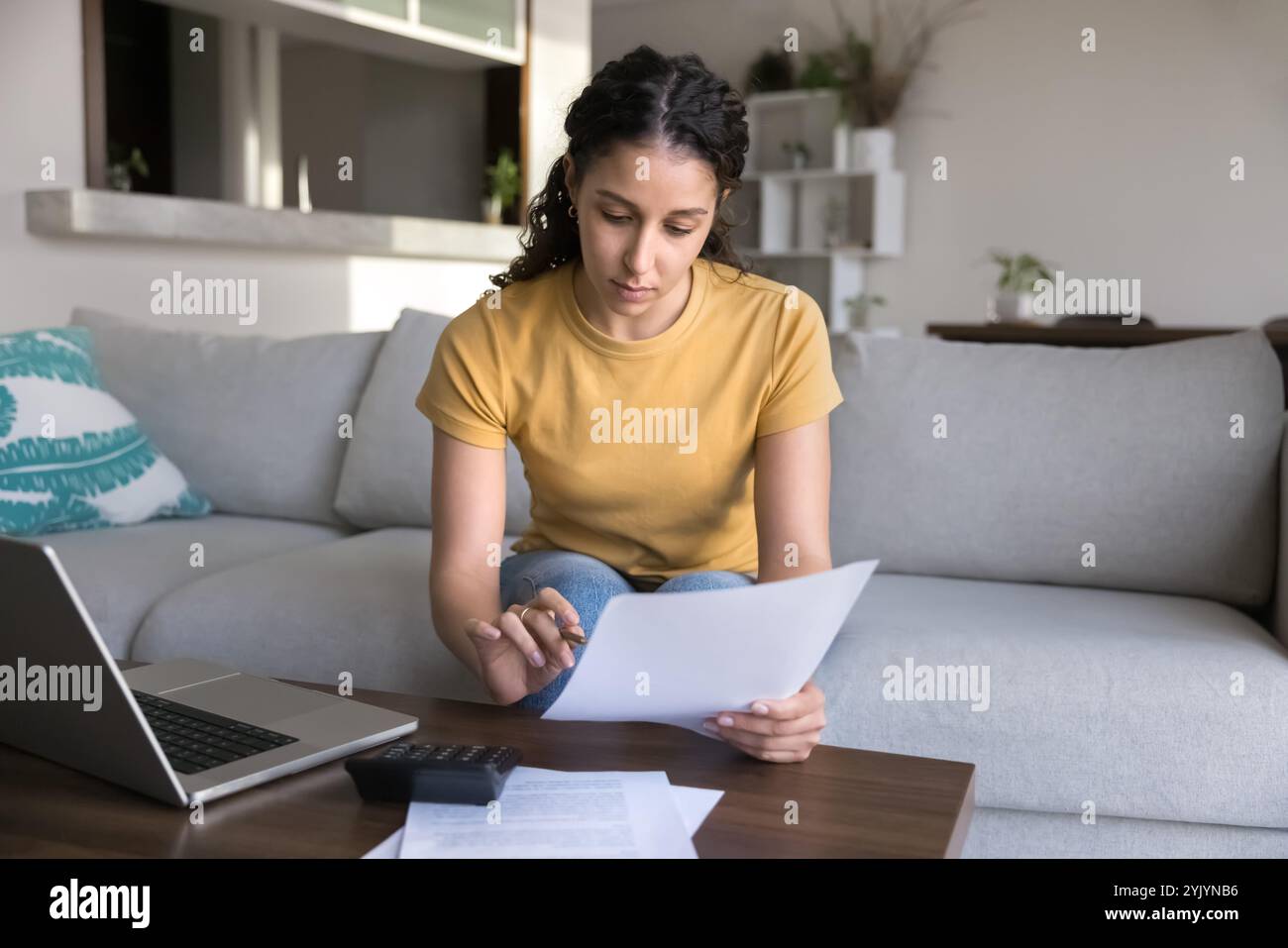 Young Latin homeowner girl reading paper invoice for payment Stock ...