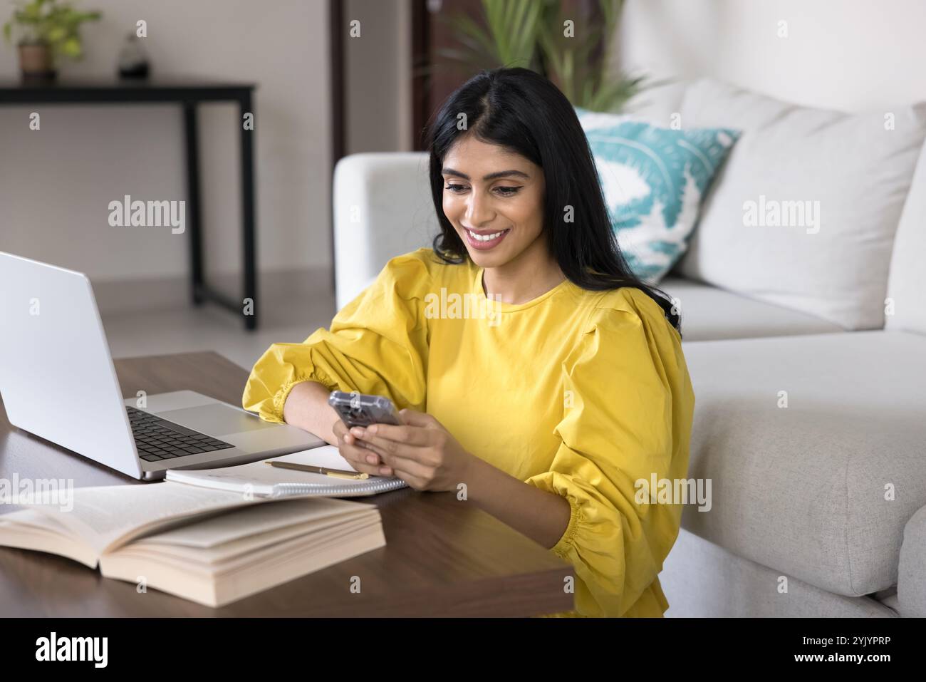Happy young Indian student using mobile phone over open book Stock ...