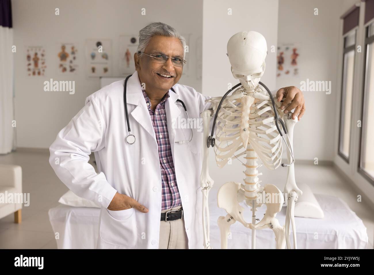 Portrait of doctor hugging skeleton posing in clinic examination room ...