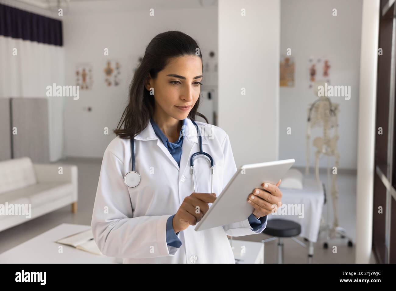 Focused young Latina female doctor wear uniform using tablet Stock ...