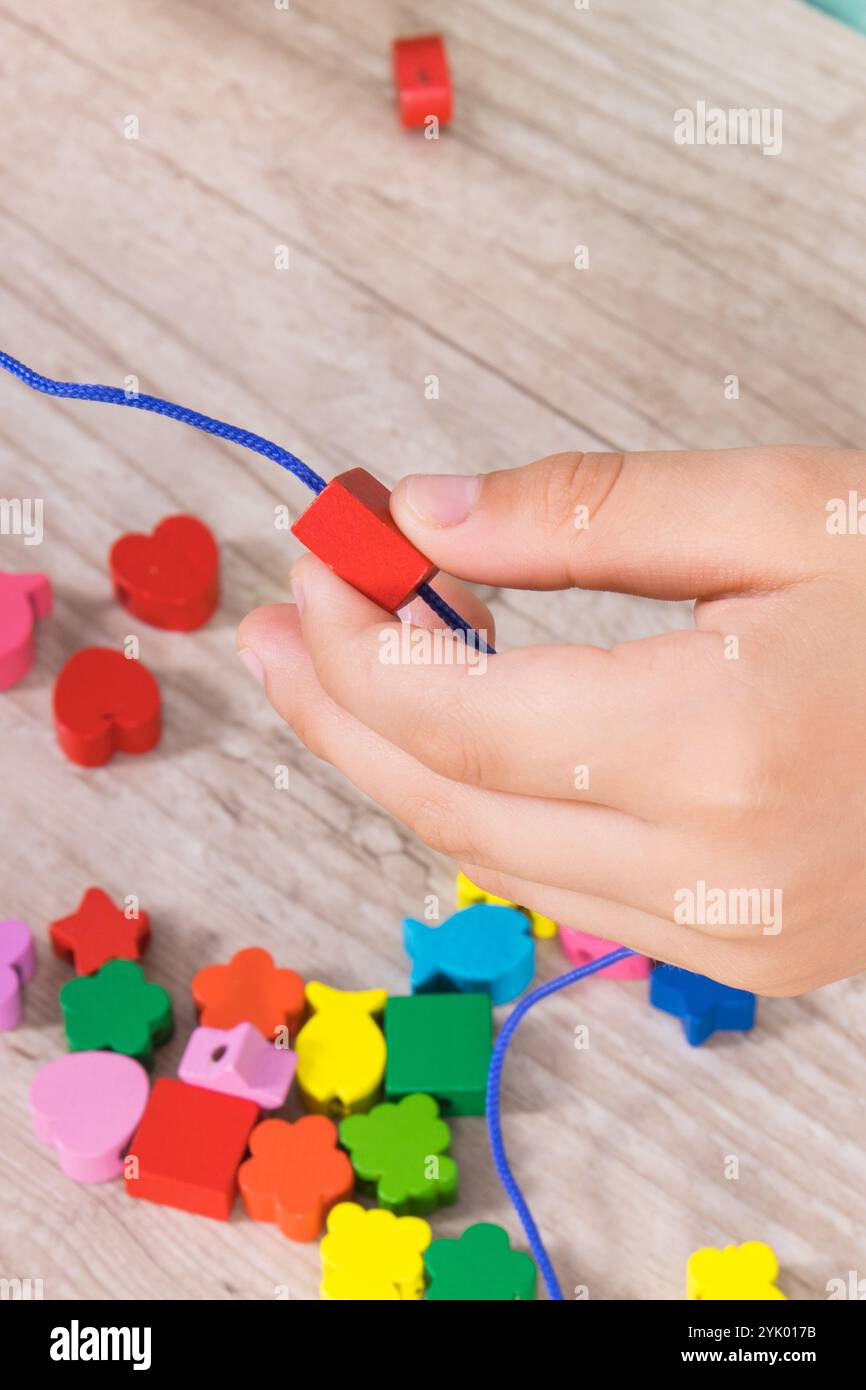Preschooler making bracelet from thread and colored beads. Development ...