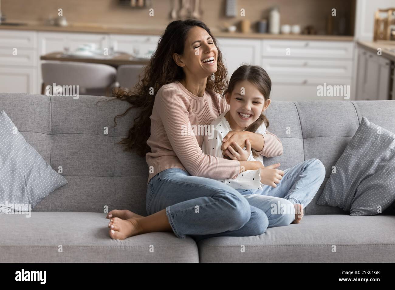 Beautiful mom cuddling tickling little 6s daughter Stock Photo - Alamy