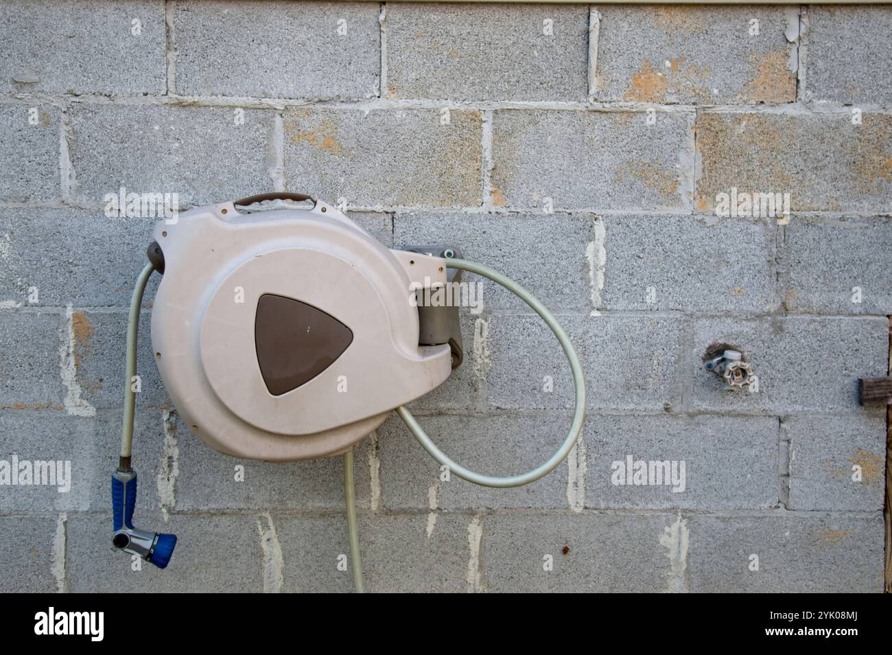 Block wall with hose reel and water spigot Stock Photo - Alamy
