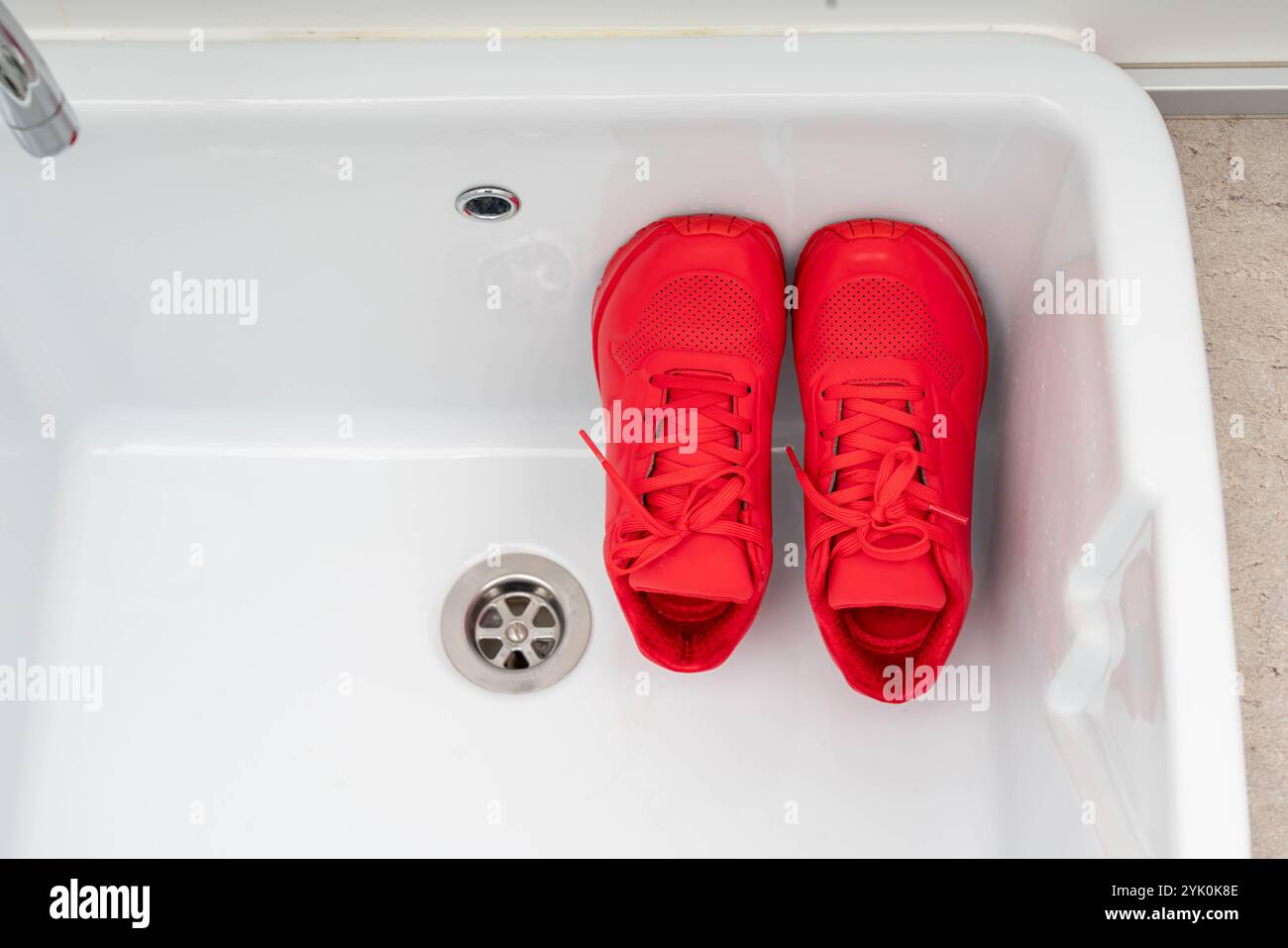 Bright red sneakers in a sink, prepared for a thorough cleaning session ...