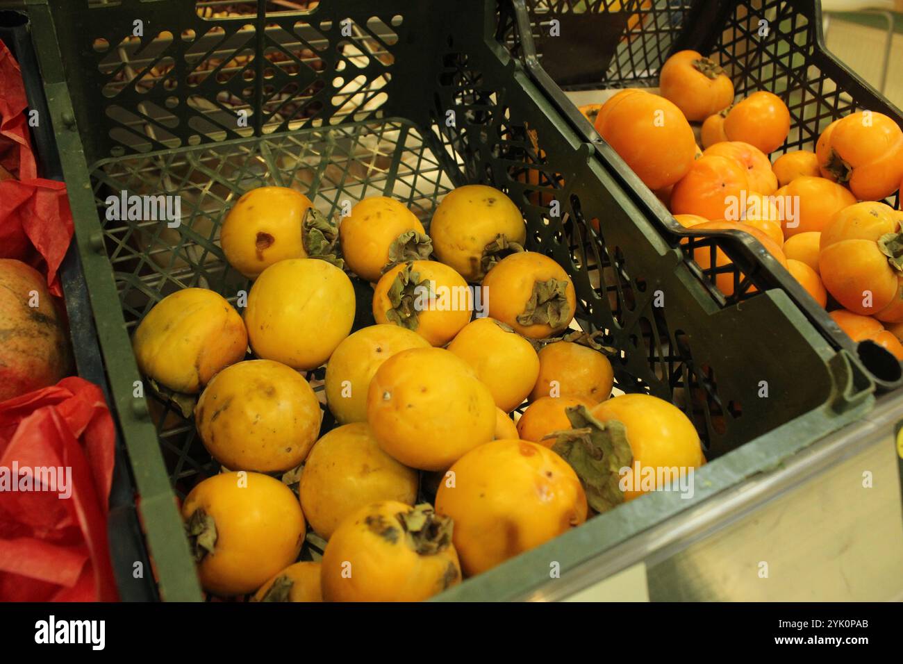 Yellow persimmons are in a plastic box in the store. Seasonal fruits ...