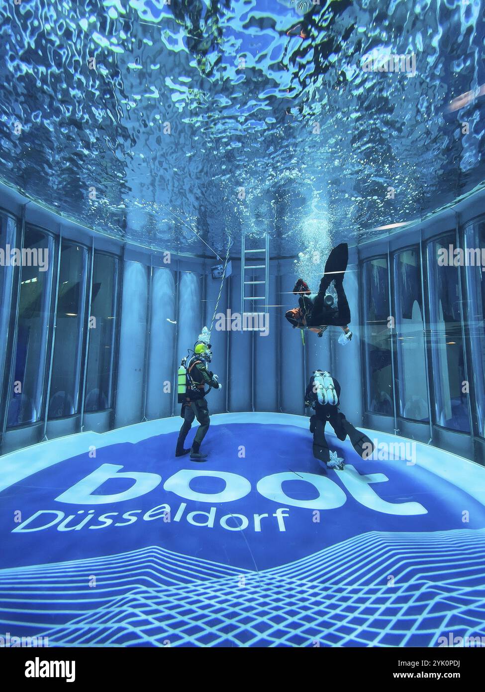 On the left diver with hose for air supply on the water surface walks ...