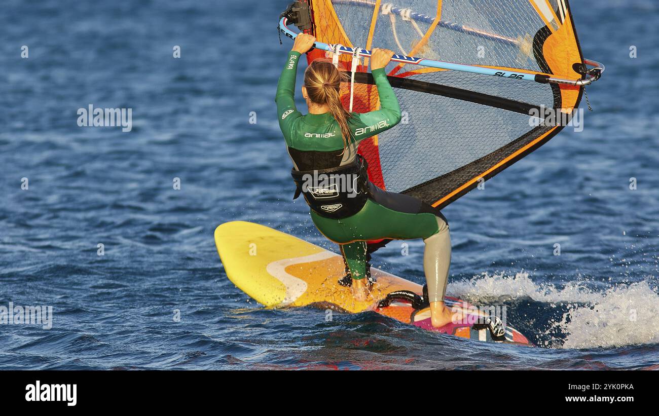 Woman in green wetsuit windsurfing on a yellow surfboard, windsurfer ...
