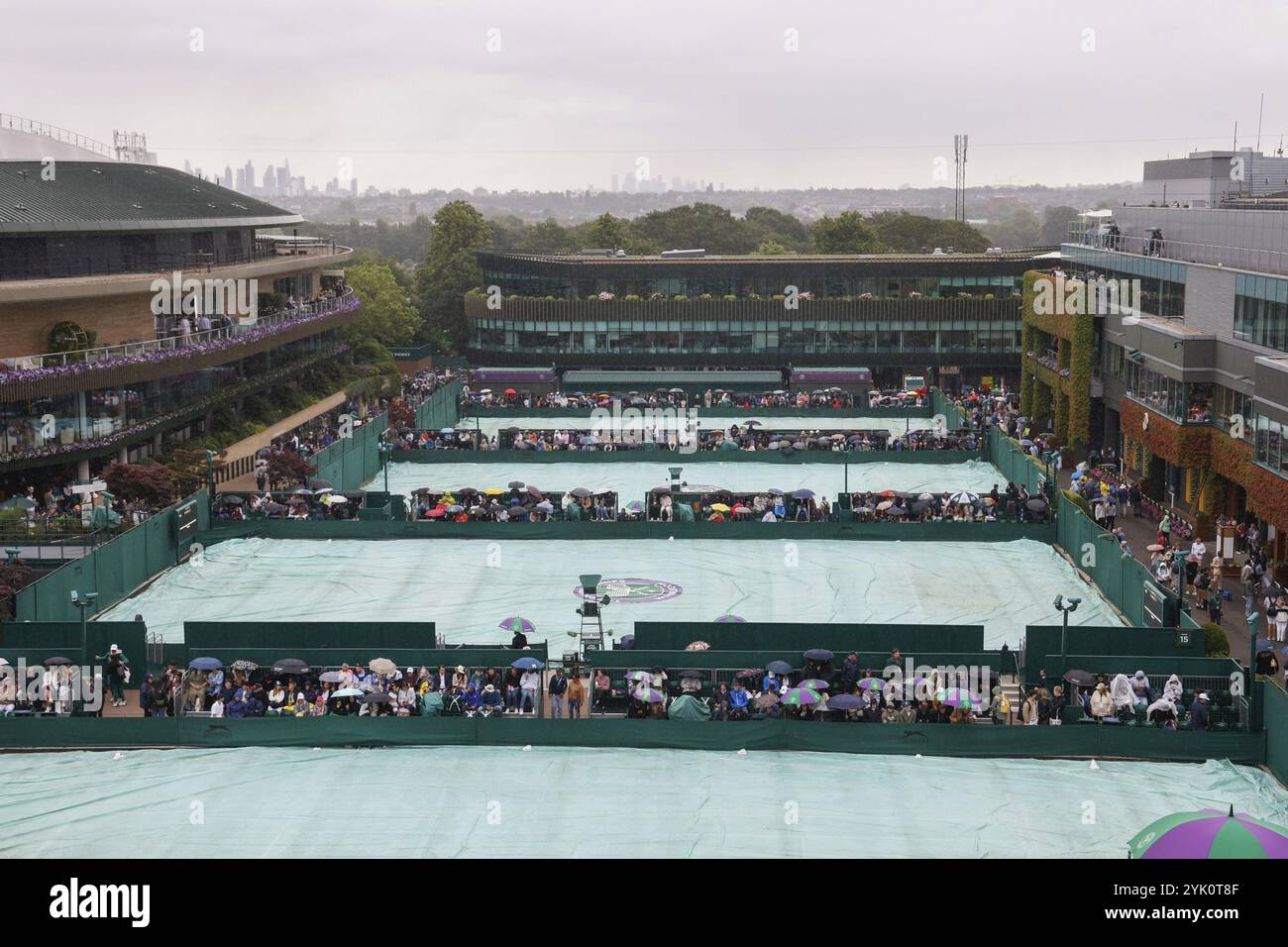 Spectators sitting in the rain on outside courts at the 2024 Wimbledon ...
