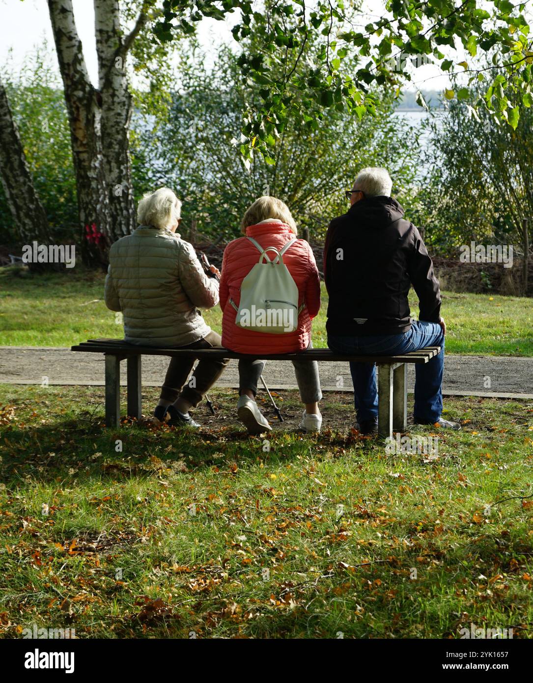 Three elderly people sitting on a bench by the lake Stock Photo - Alamy
